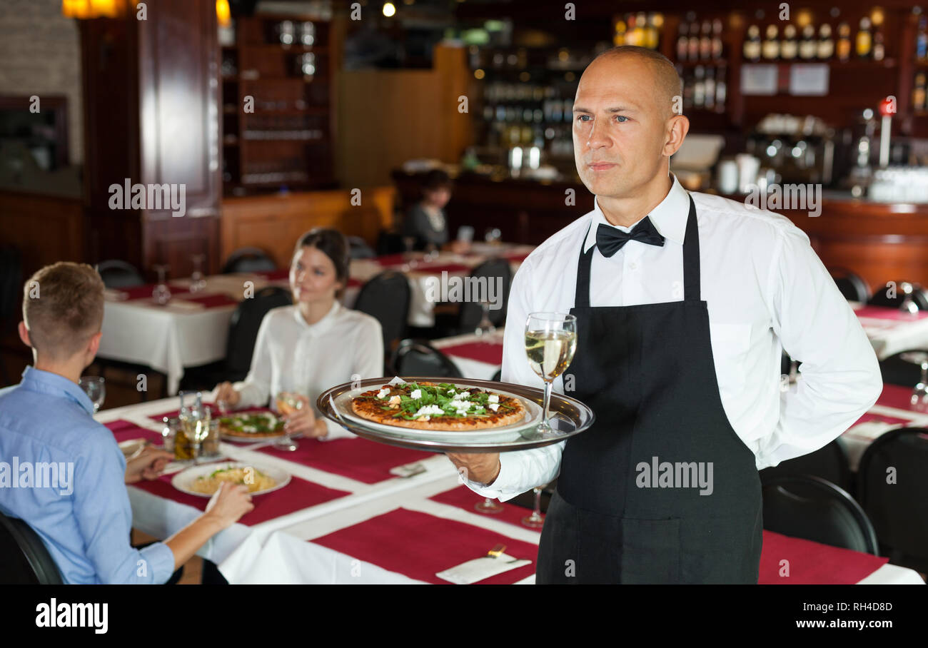 Handsome elegant waiter with serving tray welcoming to restaurant Stock ...