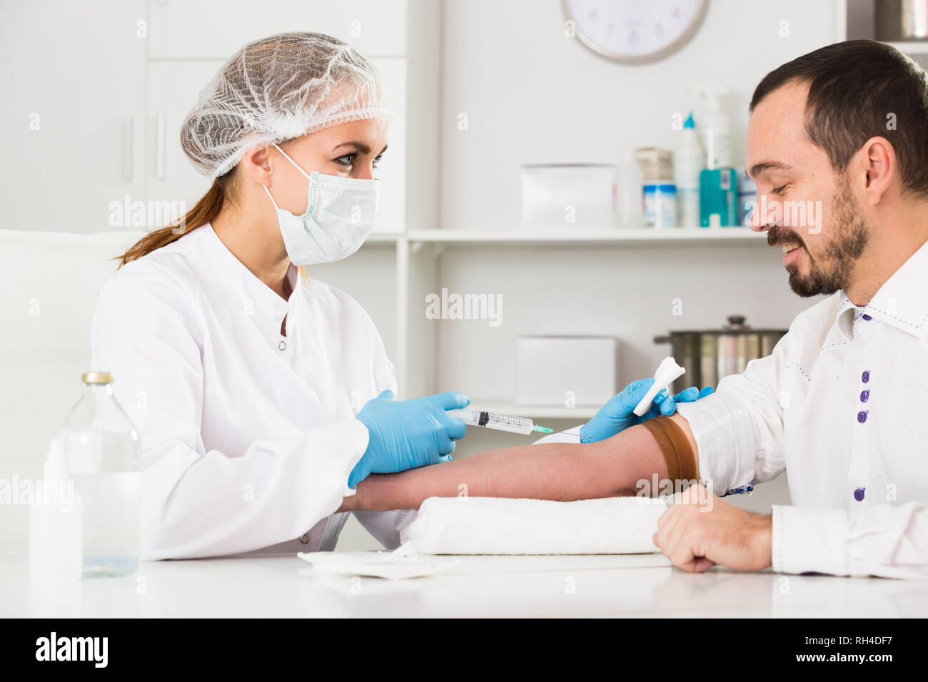 Female nurse using syringe to make injection to patient in hospital ...