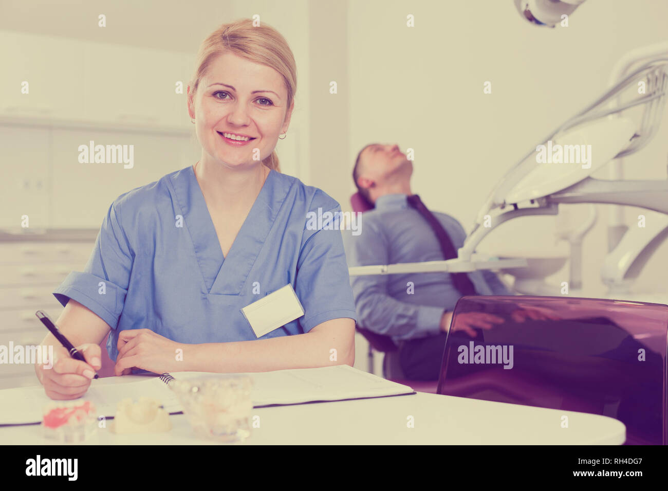 Positive female stomatologist recording diagnosis of patient at modern ...