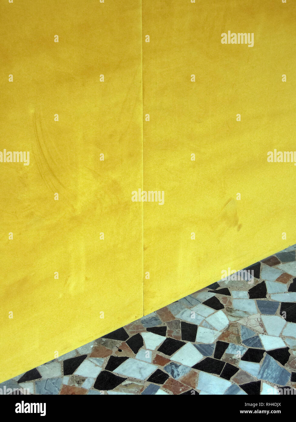 Mosaic tile below vibrant, yellow wall Stock Photo - Alamy