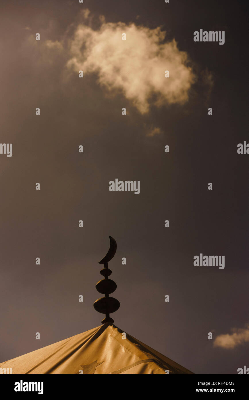 Crescent moon symbol of Islam on top of mosque below stormy sky ...