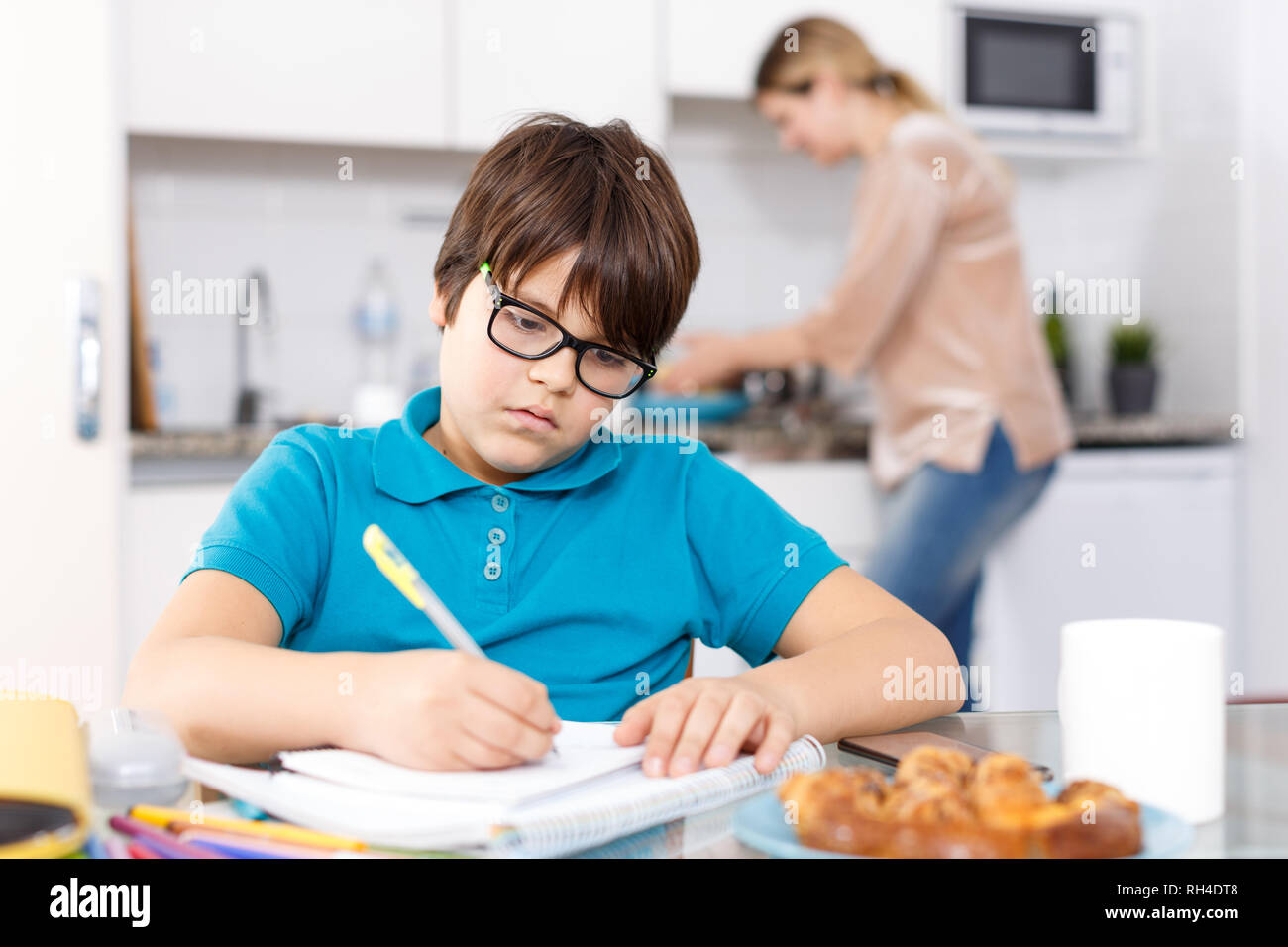 Portrait of boy studying at kitchen table and doing homework while his ...