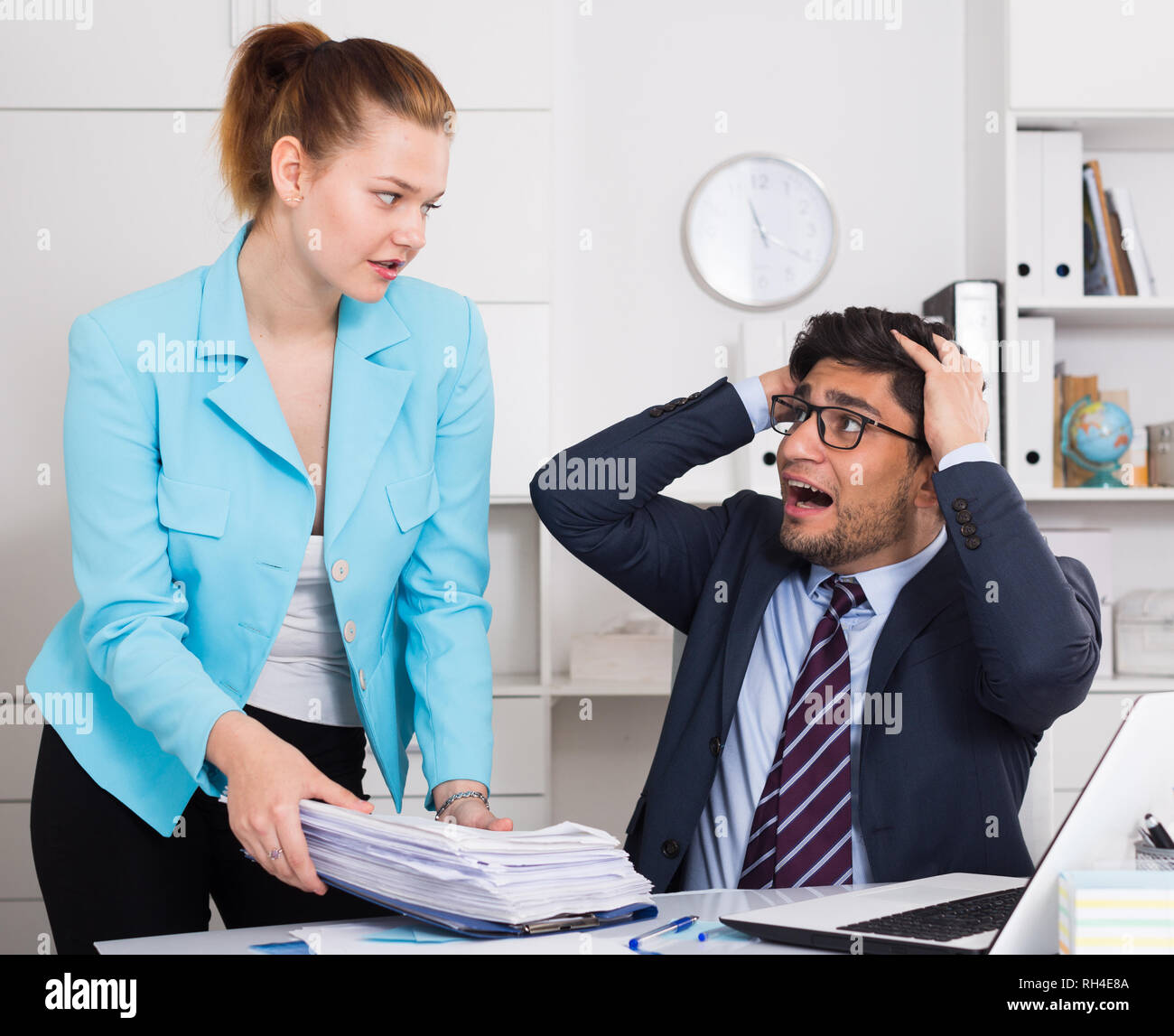 Overworked businessman looking at female colleague bringing new sheaf ...