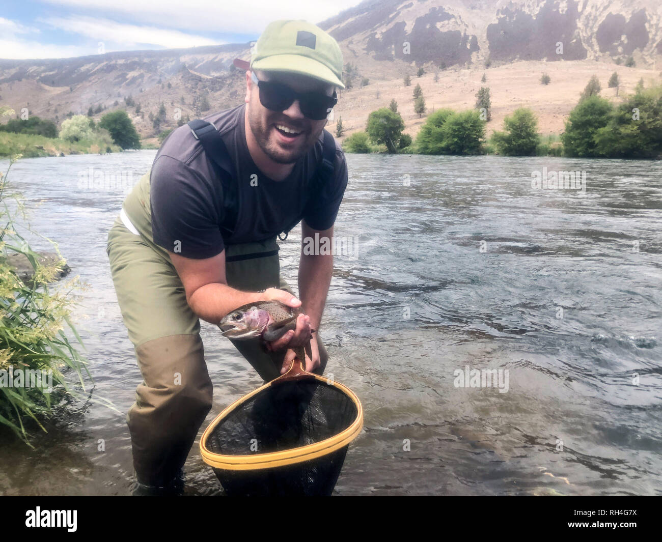 Happy fly fisherman with his catch of a ntaive redside rainbow trout on ...