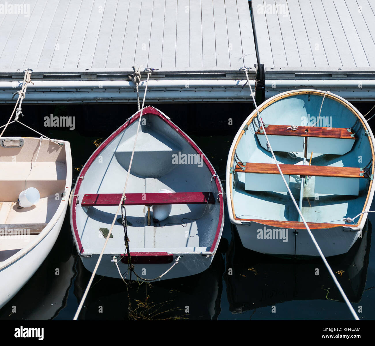 Three colorful row boats are in a perfectly straight line tied up to a ...