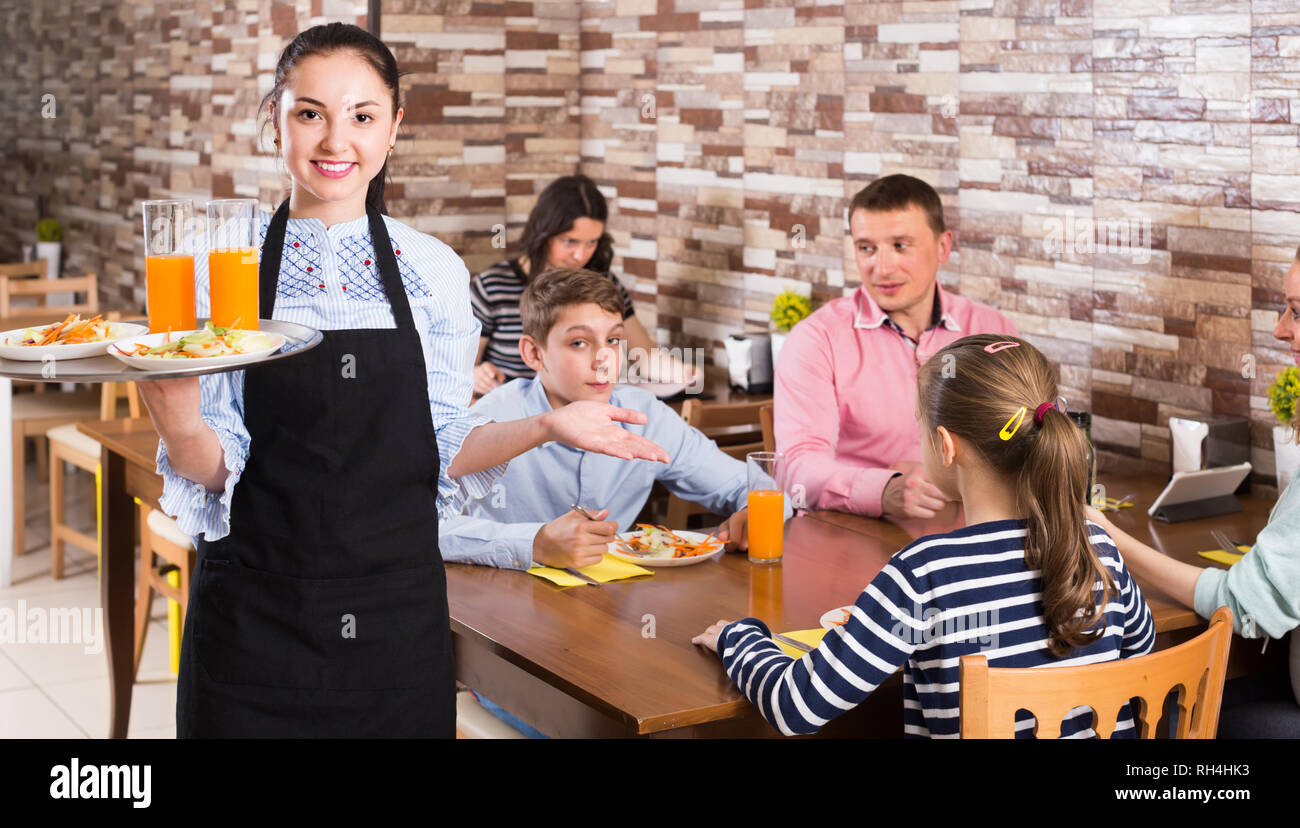 cheerful young waitress warmly welcoming guests to comfortable family ...