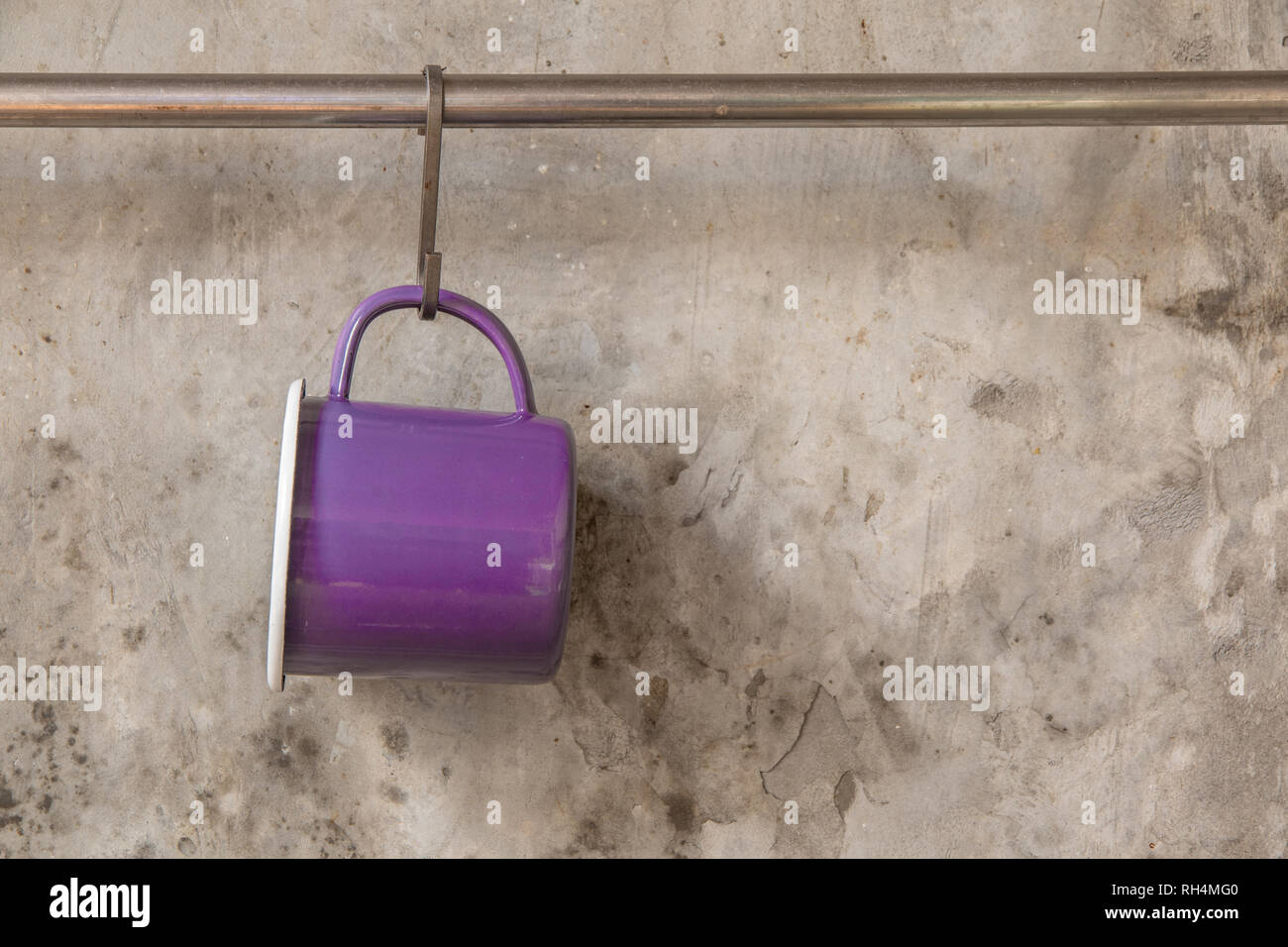 Violet tin cup hanging on stainless rail on cement wall background ...