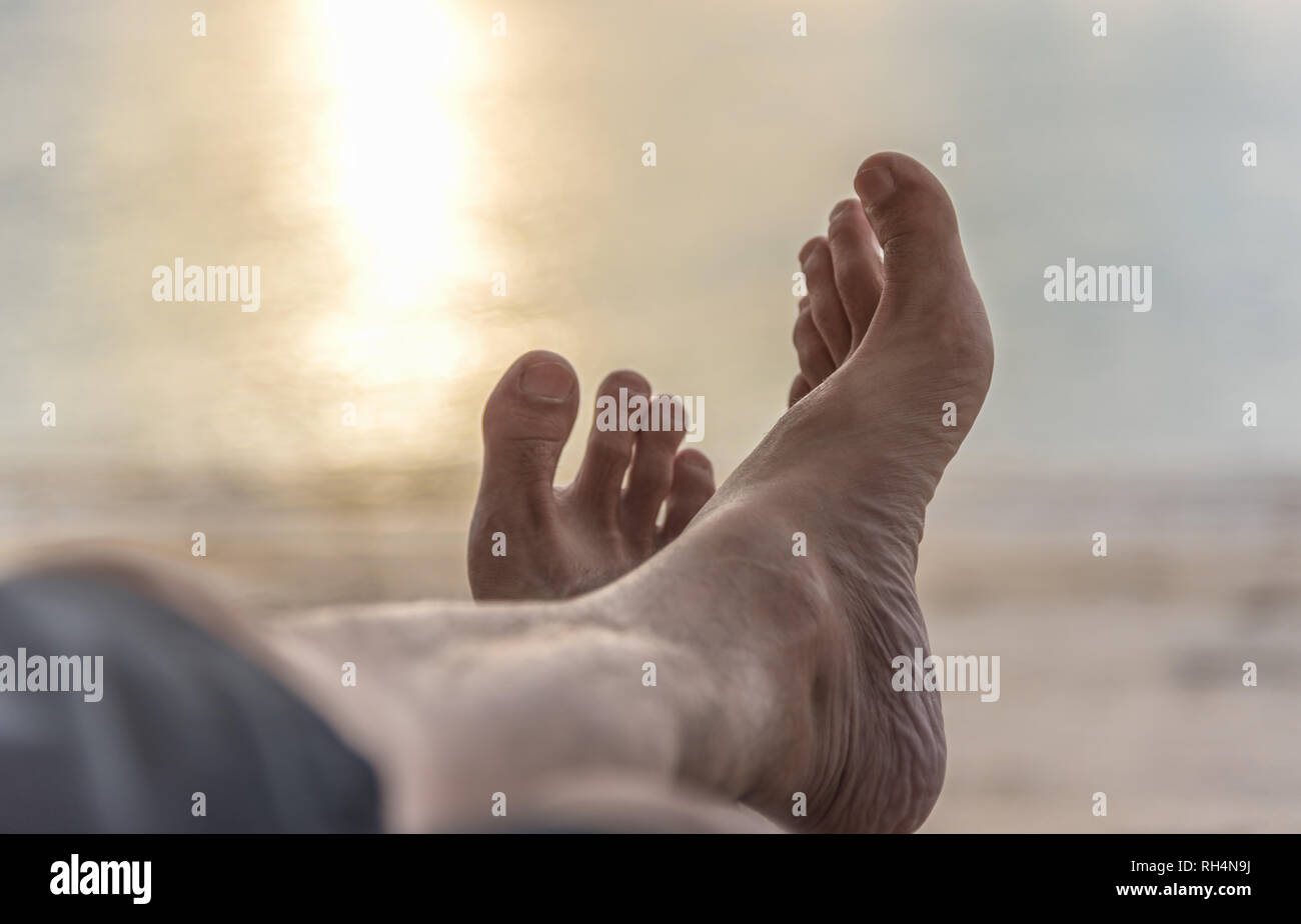 Feet of male on the beach, sunset background Stock Photo - Alamy