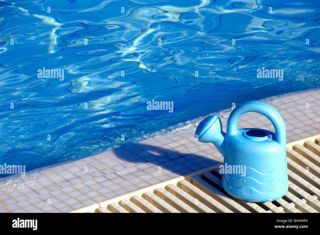 Toy watering can stands on the edge of a swimming pool Stock Photo - Alamy