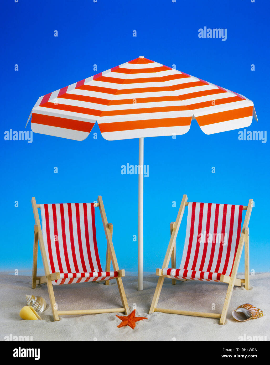 Two toys sun loungers under a parasol on the beach Stock Photo - Alamy