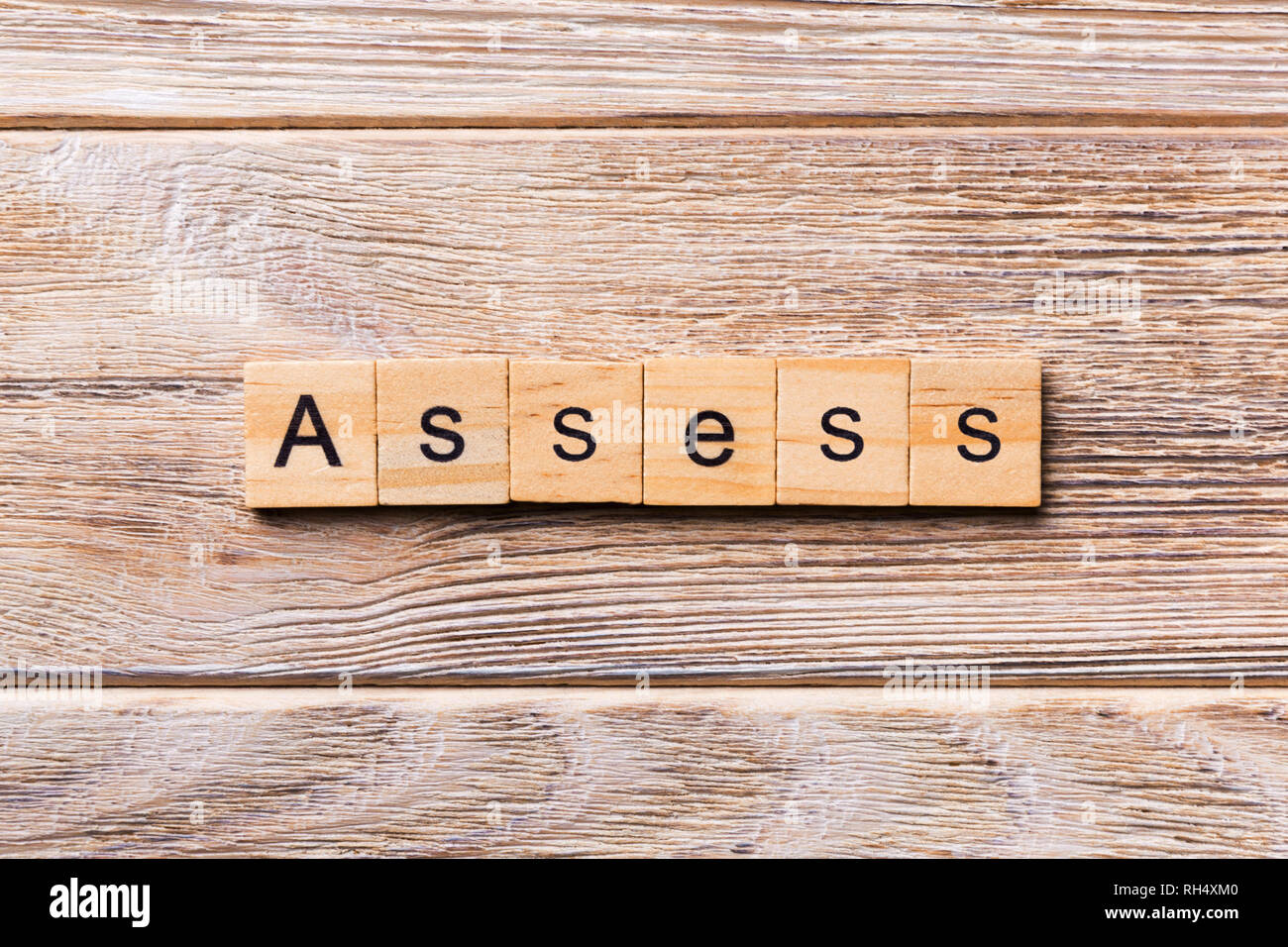 ASSESS word written on wood block. ASSESS text on wooden table for your ...