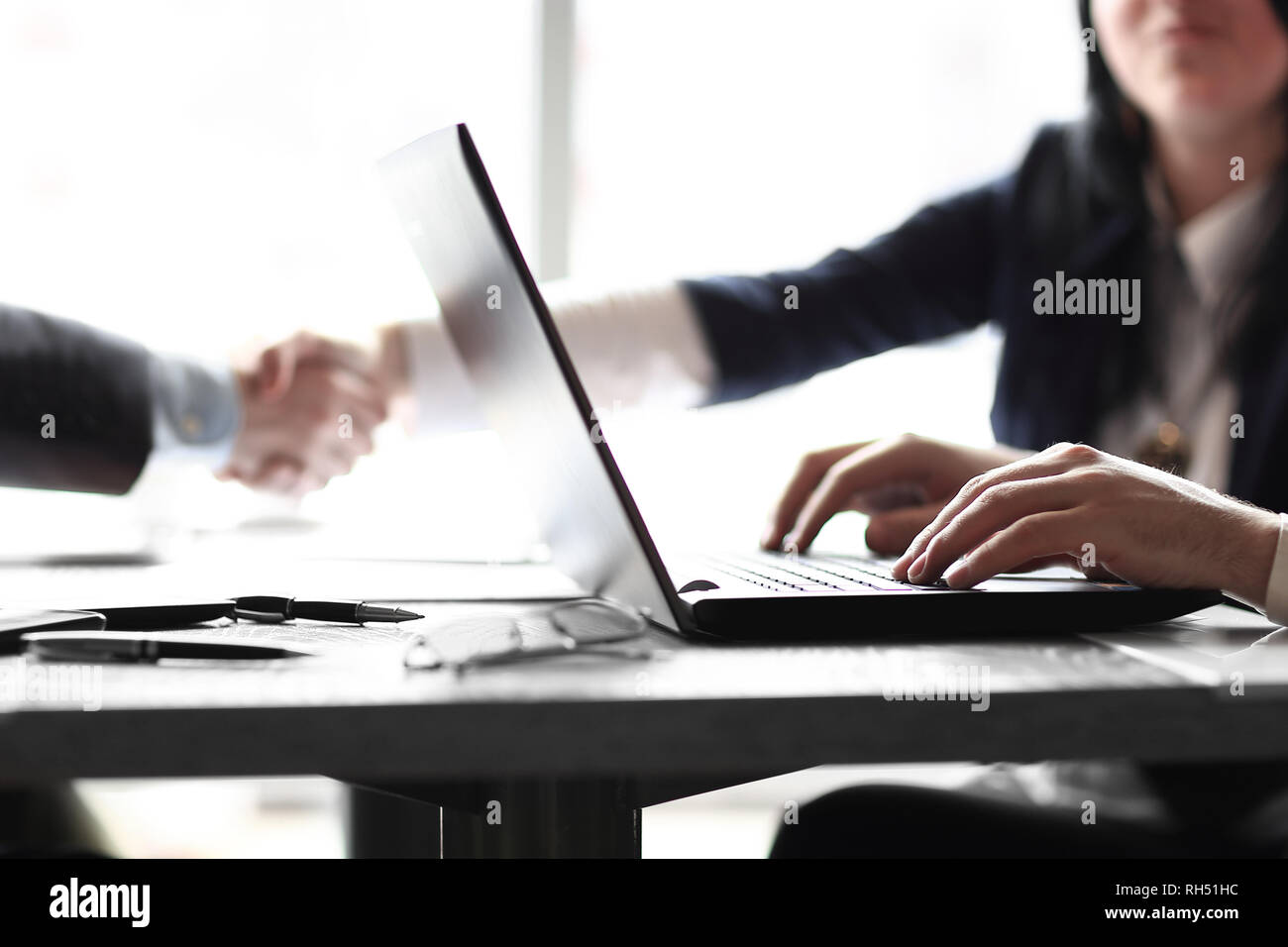 businessman working on laptop on the background of handshake of ...