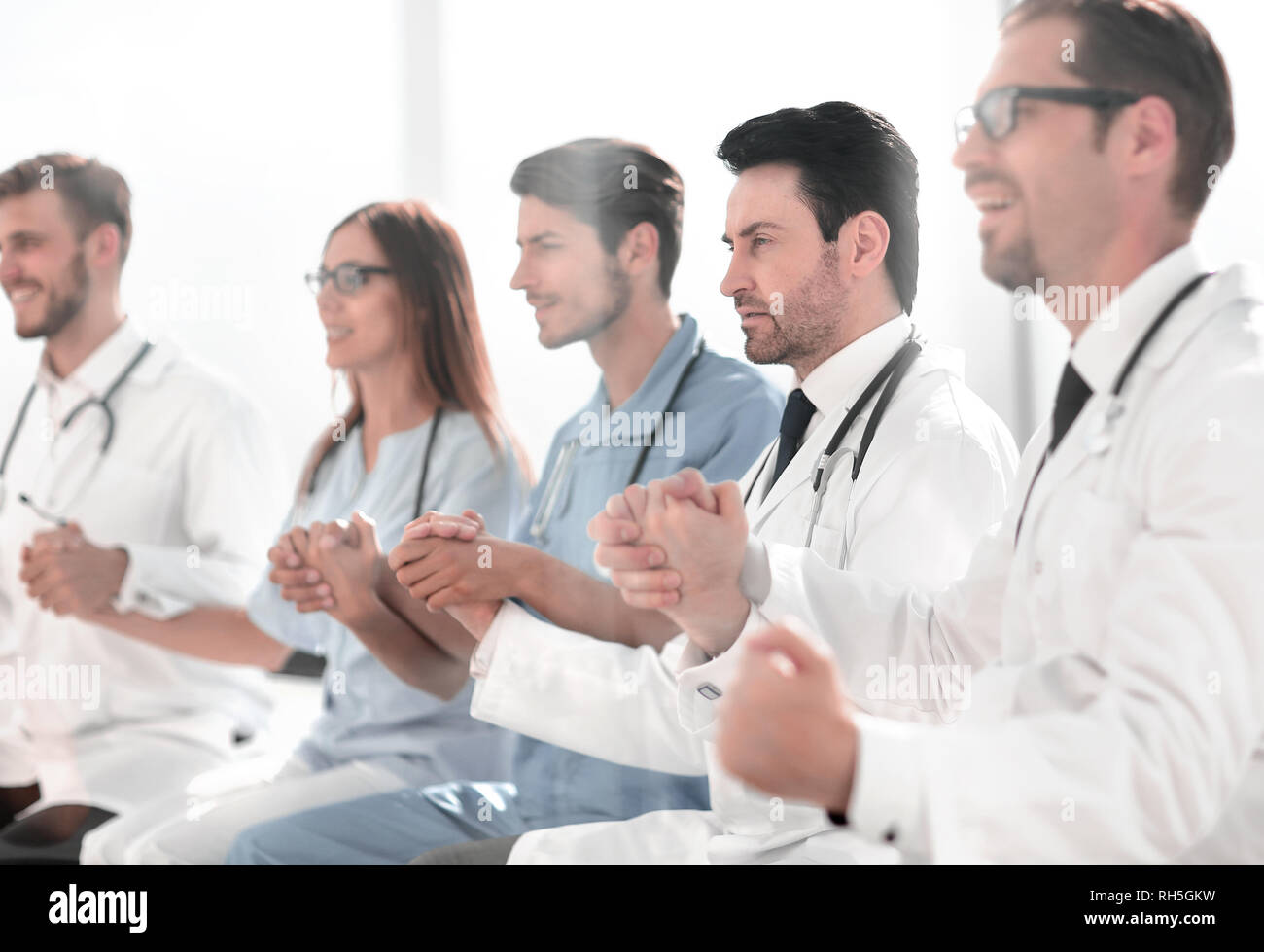 doctors sit in a row and hold hands of each other Stock Photo - Alamy