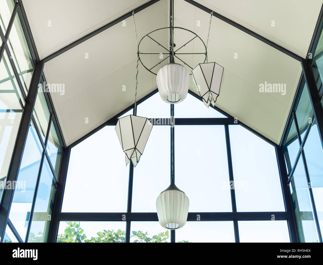 White hanging modern lamps decorated under the high roof in glass house ...