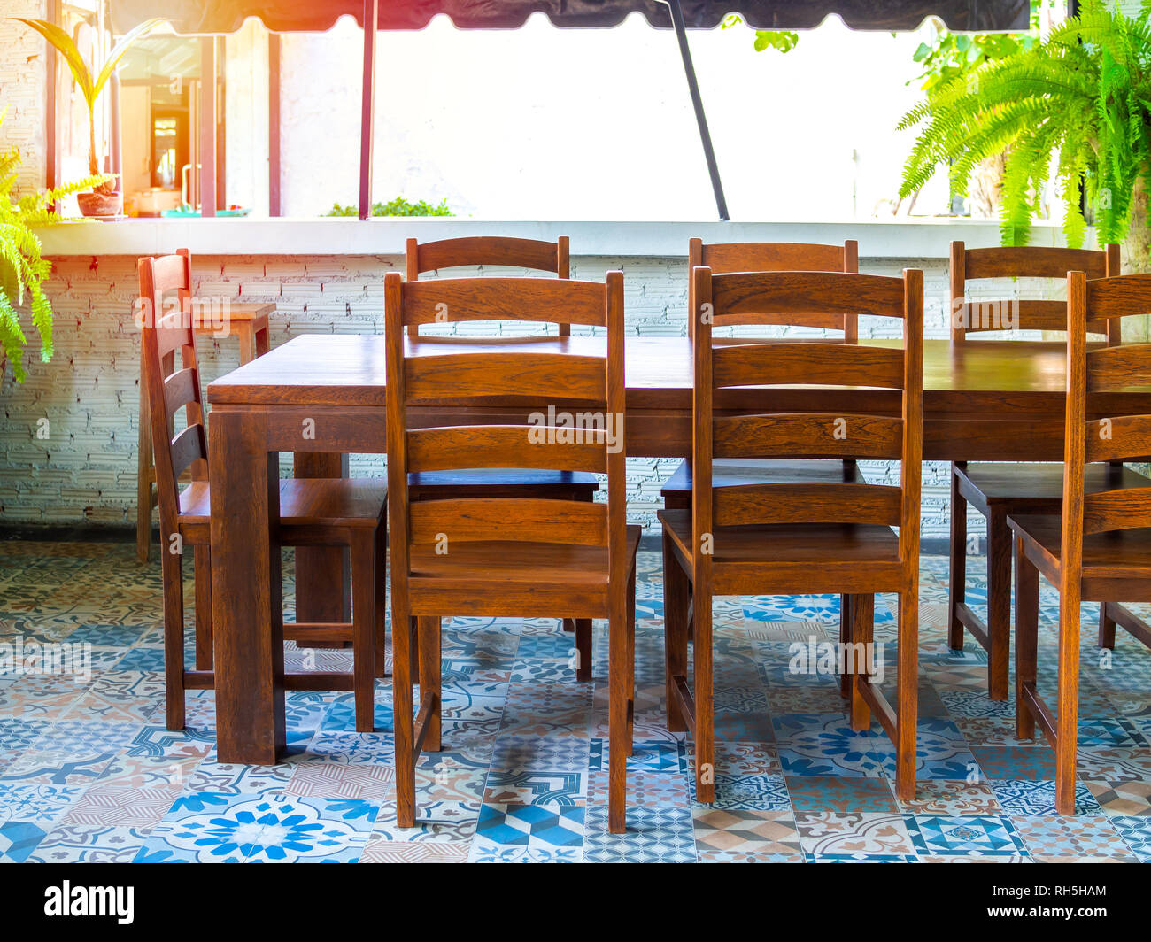 Wooden simple table and chairs on vintage tile floor near white brick ...