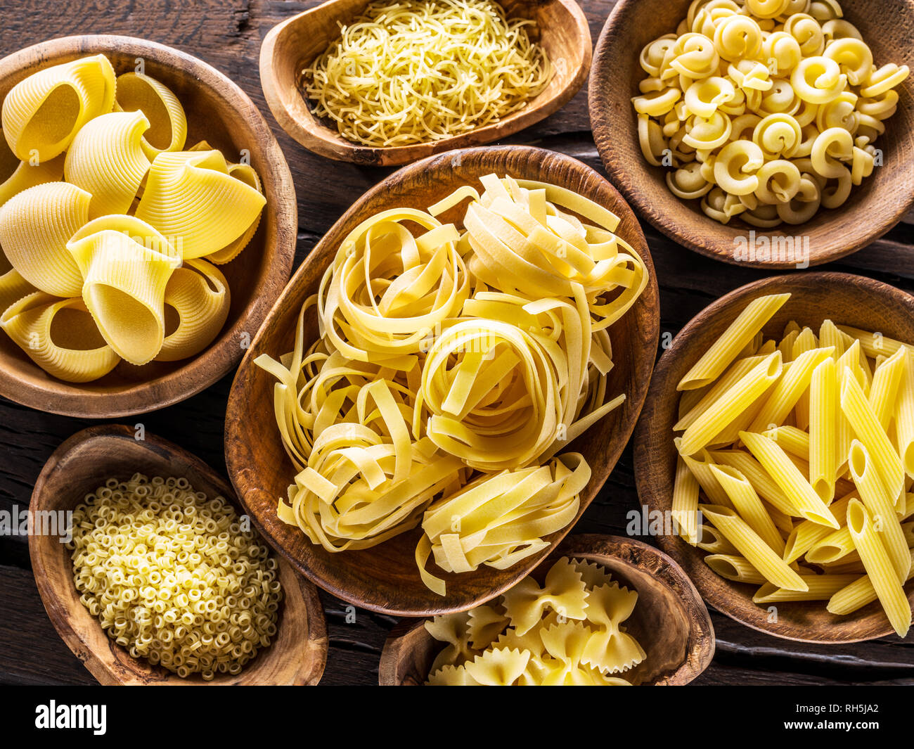 Different pasta types in wooden bowls on the table. Top view Stock ...