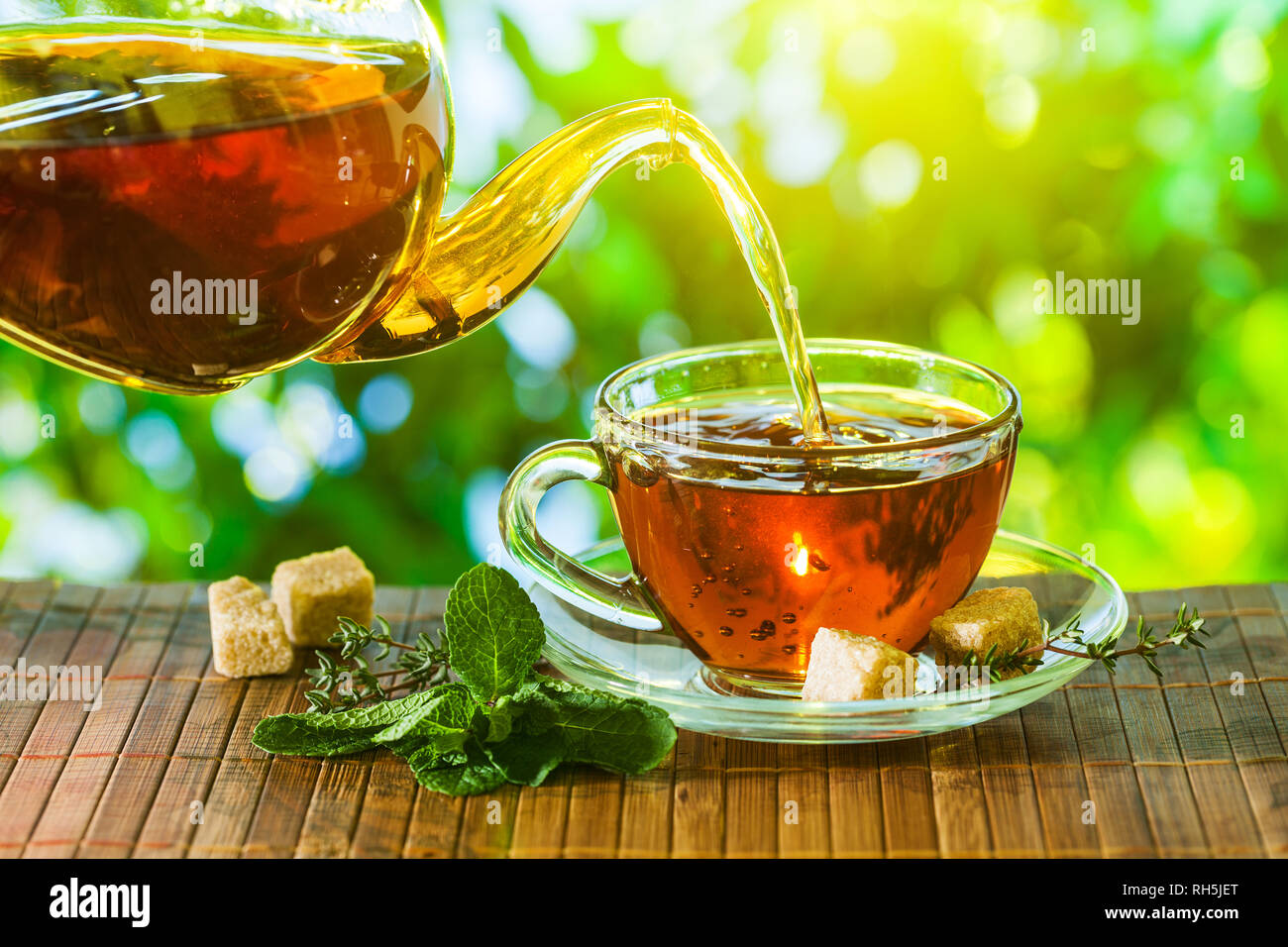 Tea time. Pouring out hot tea into a cup. Green nature background Stock ...