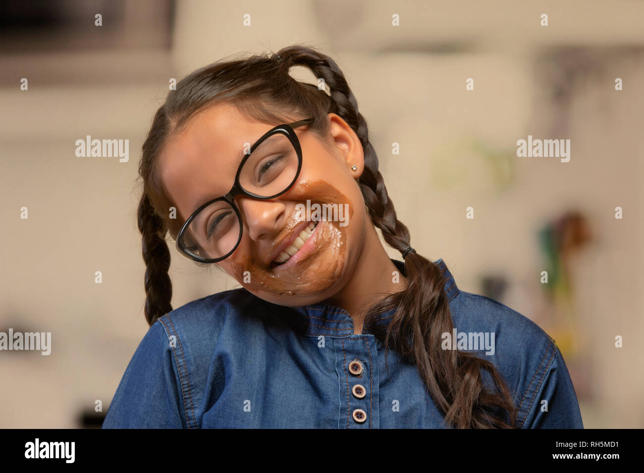 Portrait Of A Smiling Girl In Spectacles With Chocolate Marks Around Her Mouth With Head Bent
