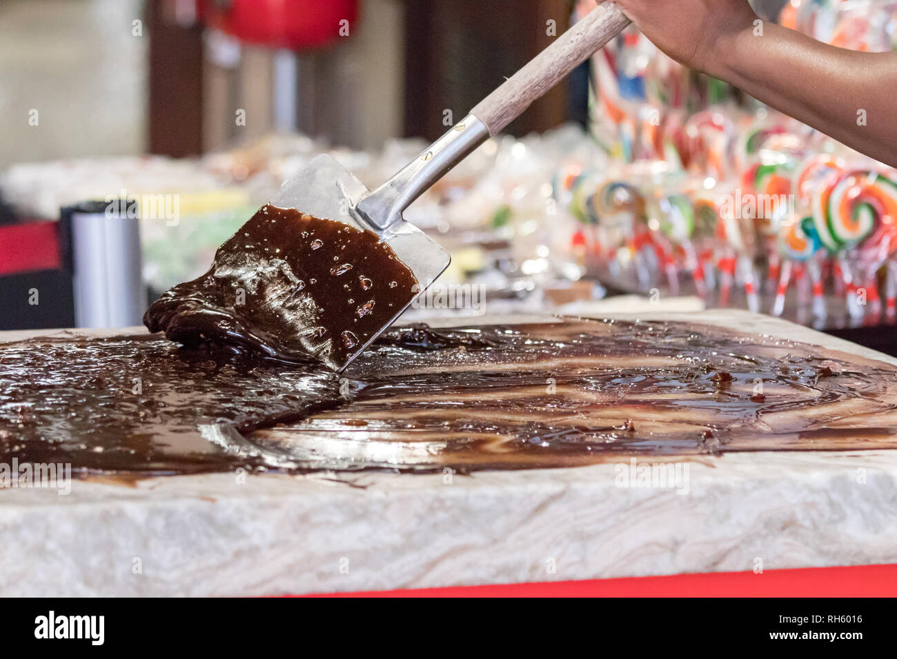 Closeup of an artisan chocolate worker mixing melting chocolate with ...