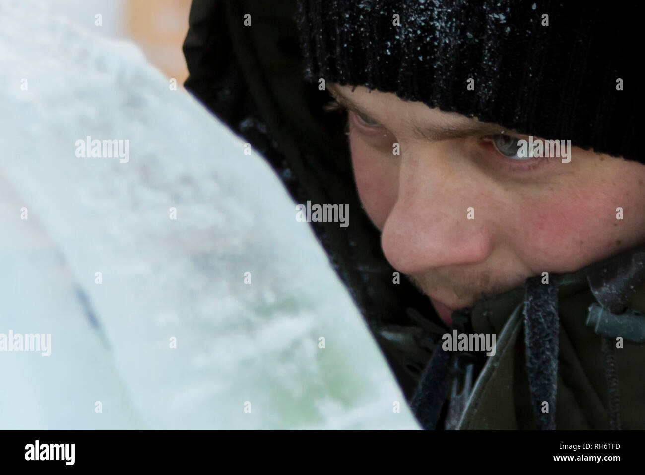 The sculptor cuts an ice figure out of ice with a chisel for Christmas ...