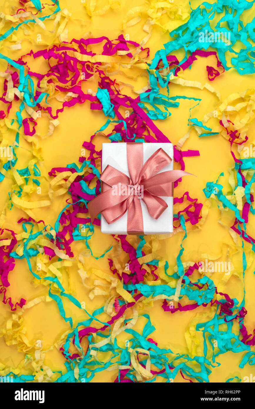 Gift box with colored streamers bright yellow background. A top view of ...