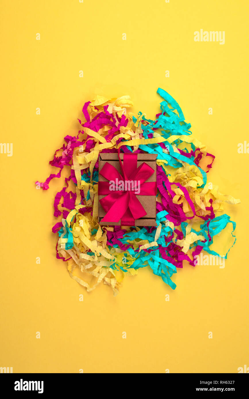 Gift box with colored streamers bright yellow background. A top view of ...