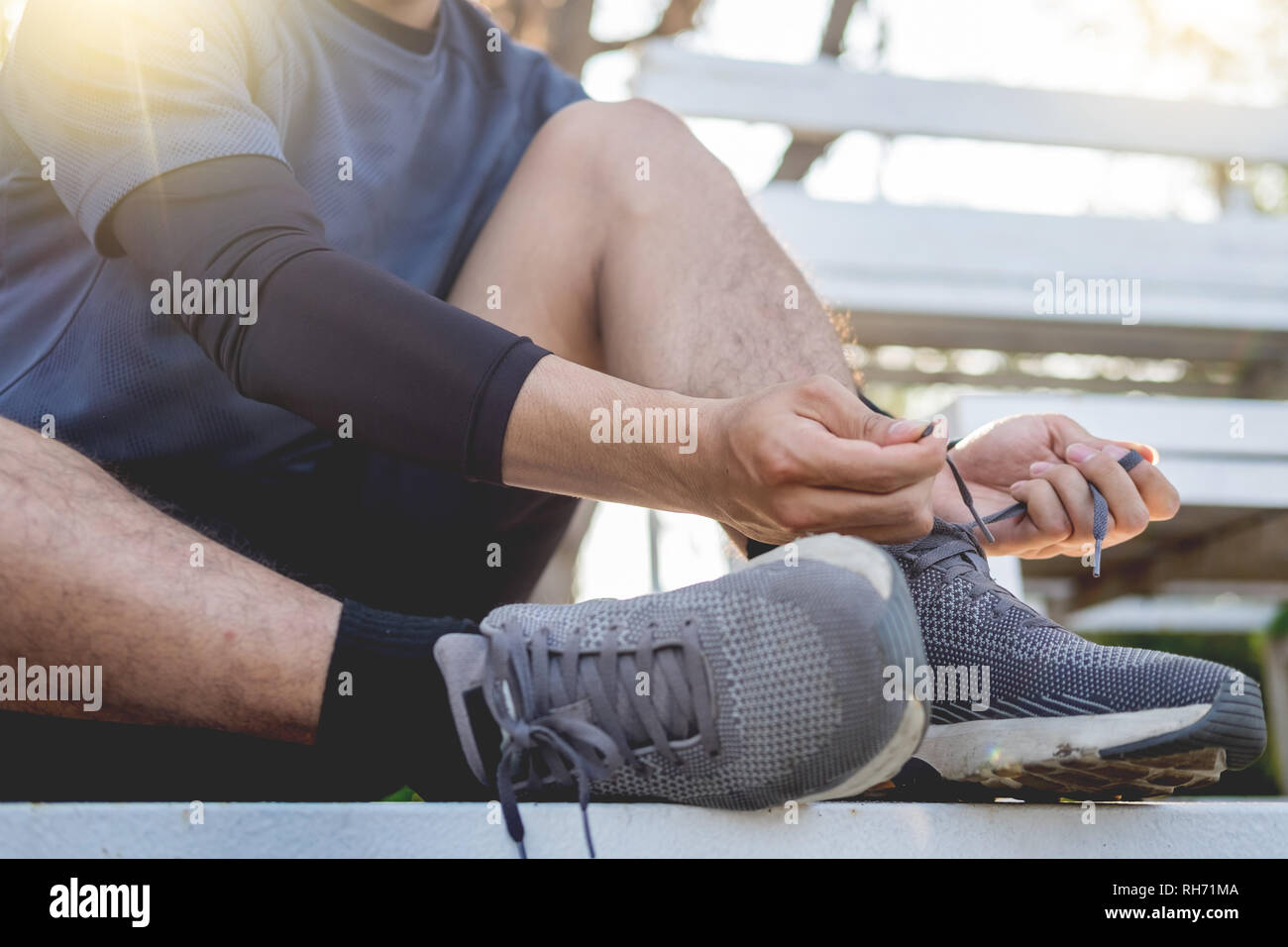 Male athlete tying shoe laces in minimalistic barefoot sneakers getting ...