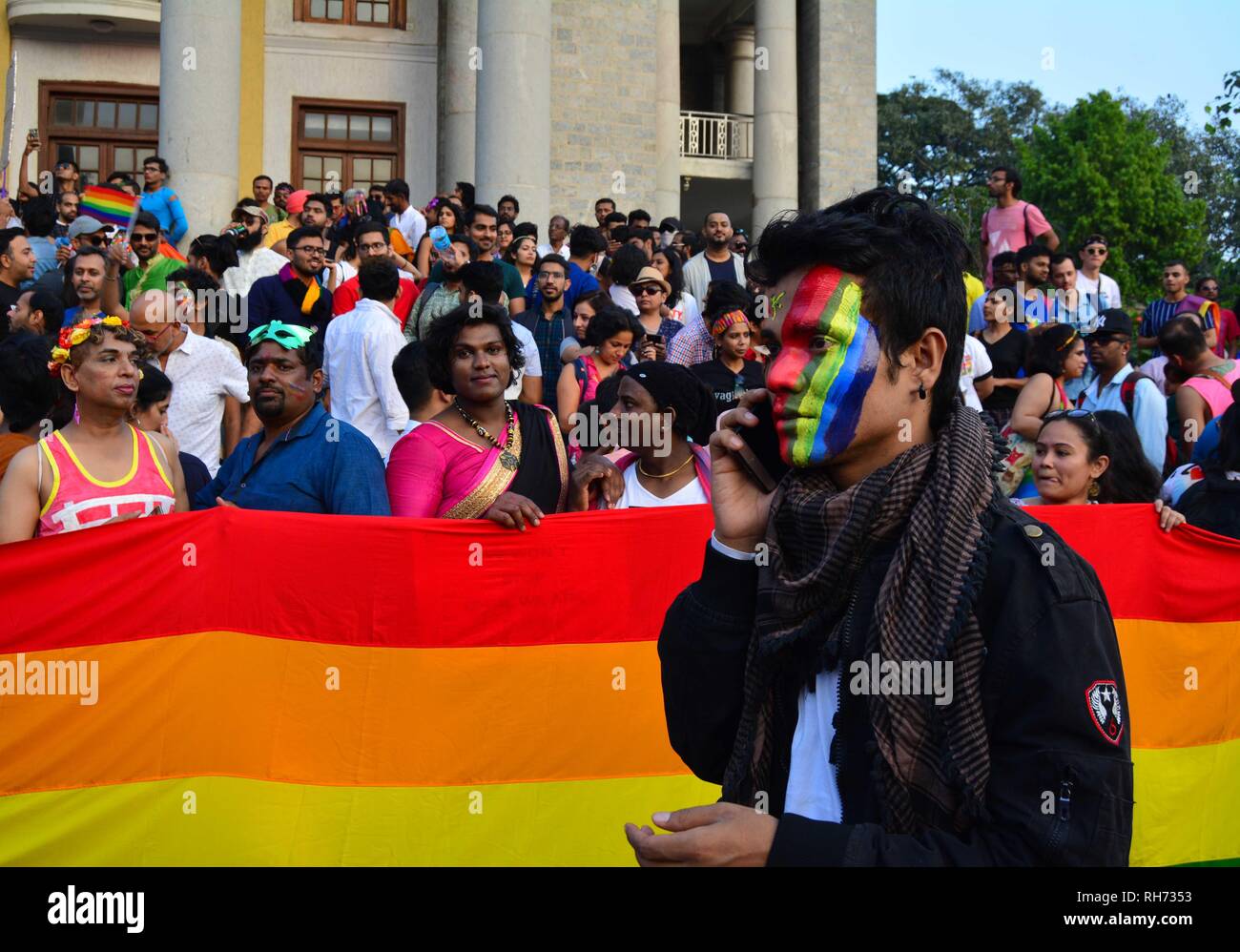 A man walks past the pride flag with his face painted in pride colours ...