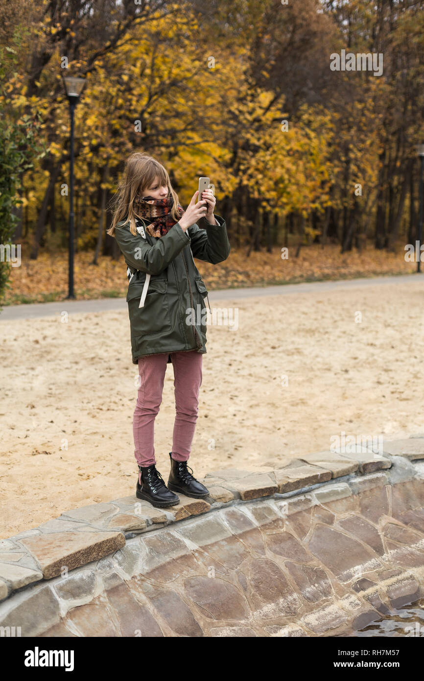 Tween girl using camera phone in autumn park Stock Photo - Alamy