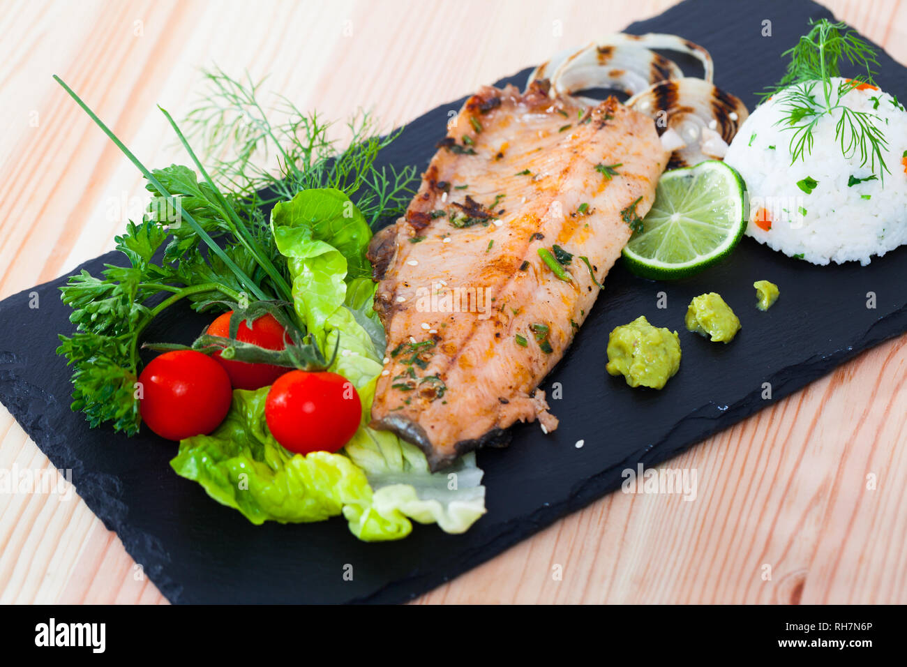 Picture of deliciously fried trout fillet with rice and greens on black ...
