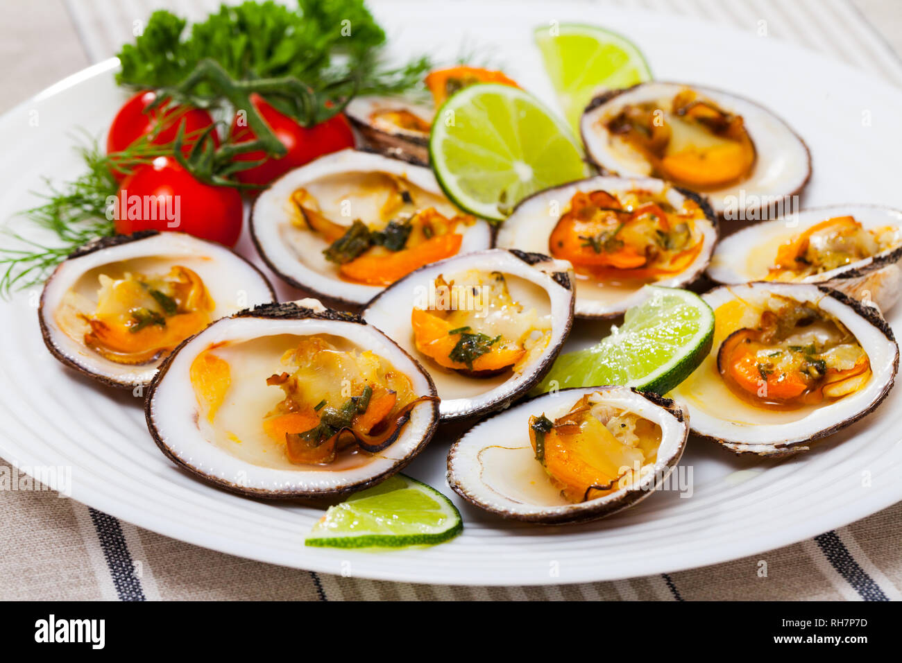 Plate of delicious oven baked clams with sauce and lime Stock Photo - Alamy