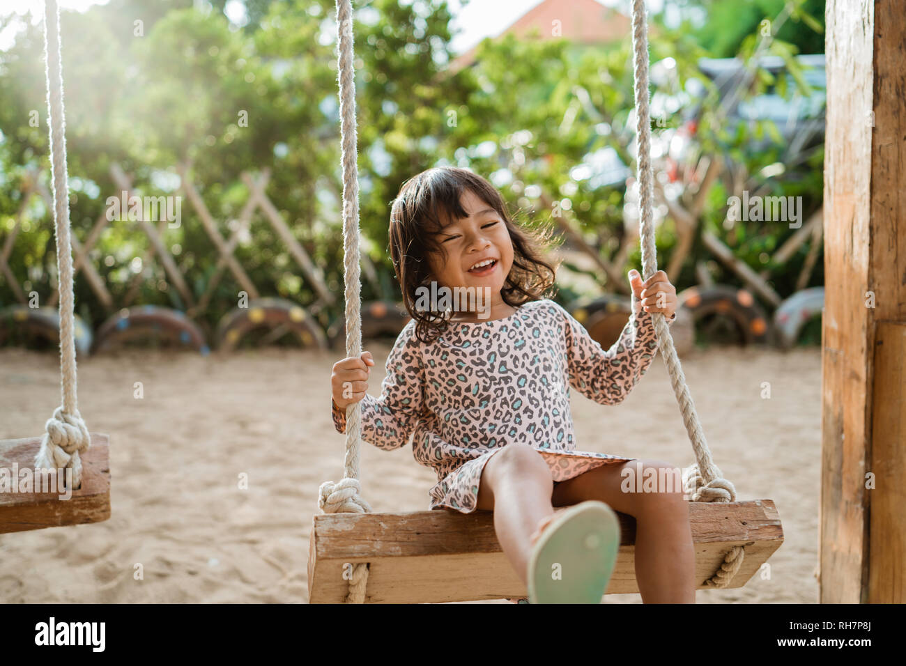 portrait of a happiness little girl laughing when playing a swing alone ...