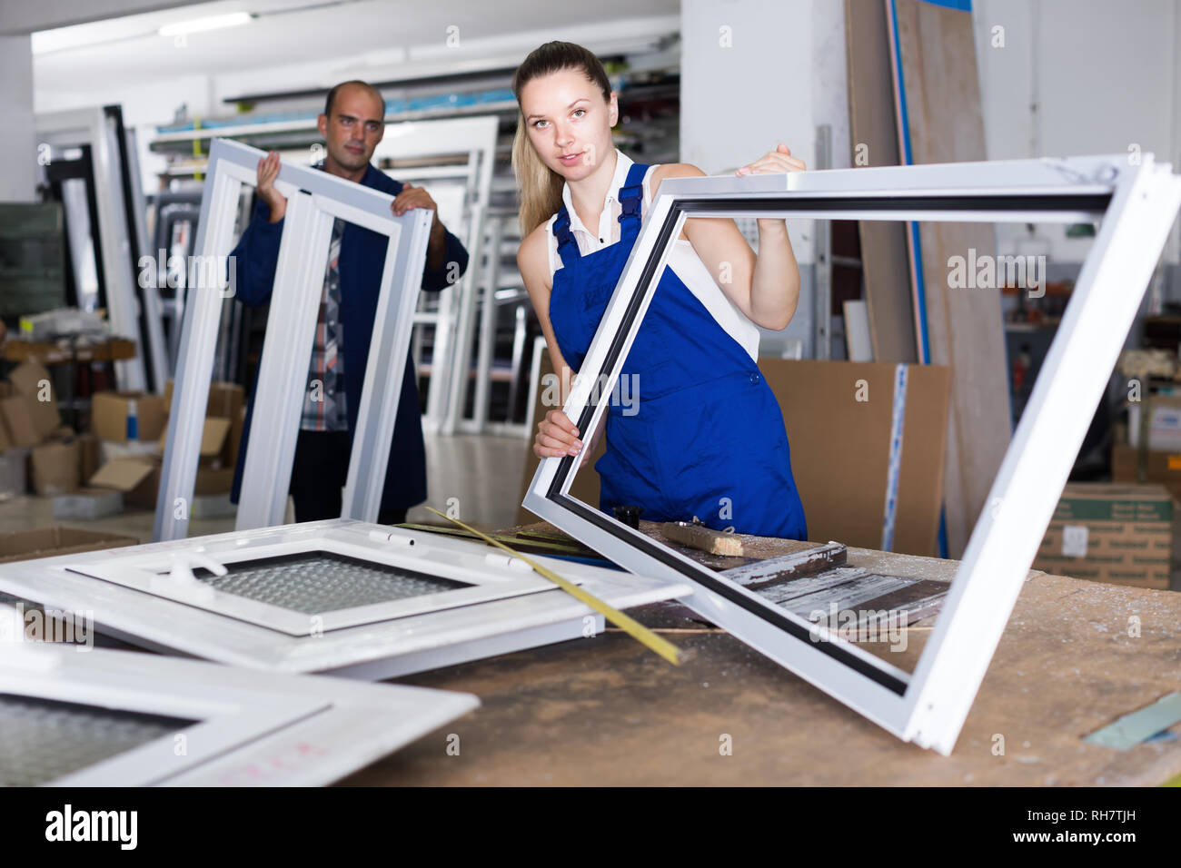 Young smiling woman worker demonstration plastic window frame in ...