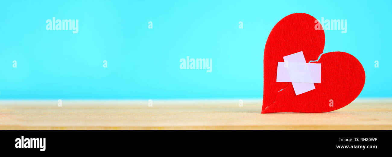 A red felt heart broken into two halves, glued together by a plaster on ...