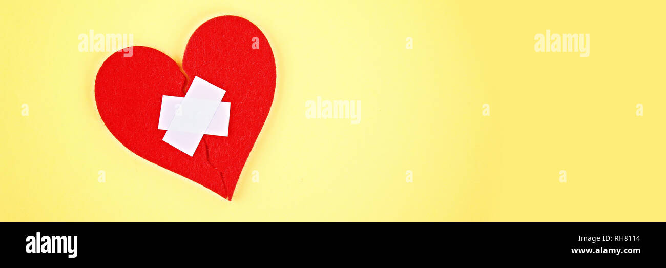 A red felt heart broken into two halves, glued together by a plaster on ...