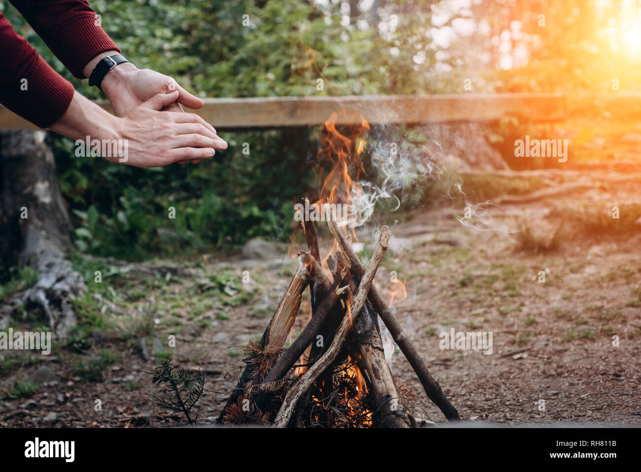 Summer camp. Hands man near a campfire at sunset time in the forest ...