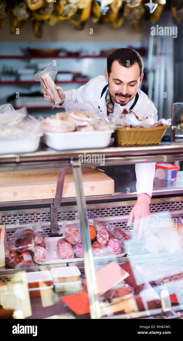Positive Russian Male Shop Assistant Demonstrating Sliced Bacon In