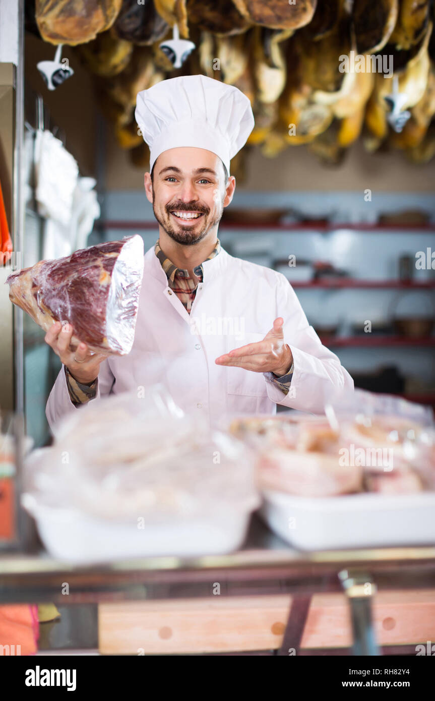 Happy American Male Shop Assistant Demonstrating Piece Of Meat In