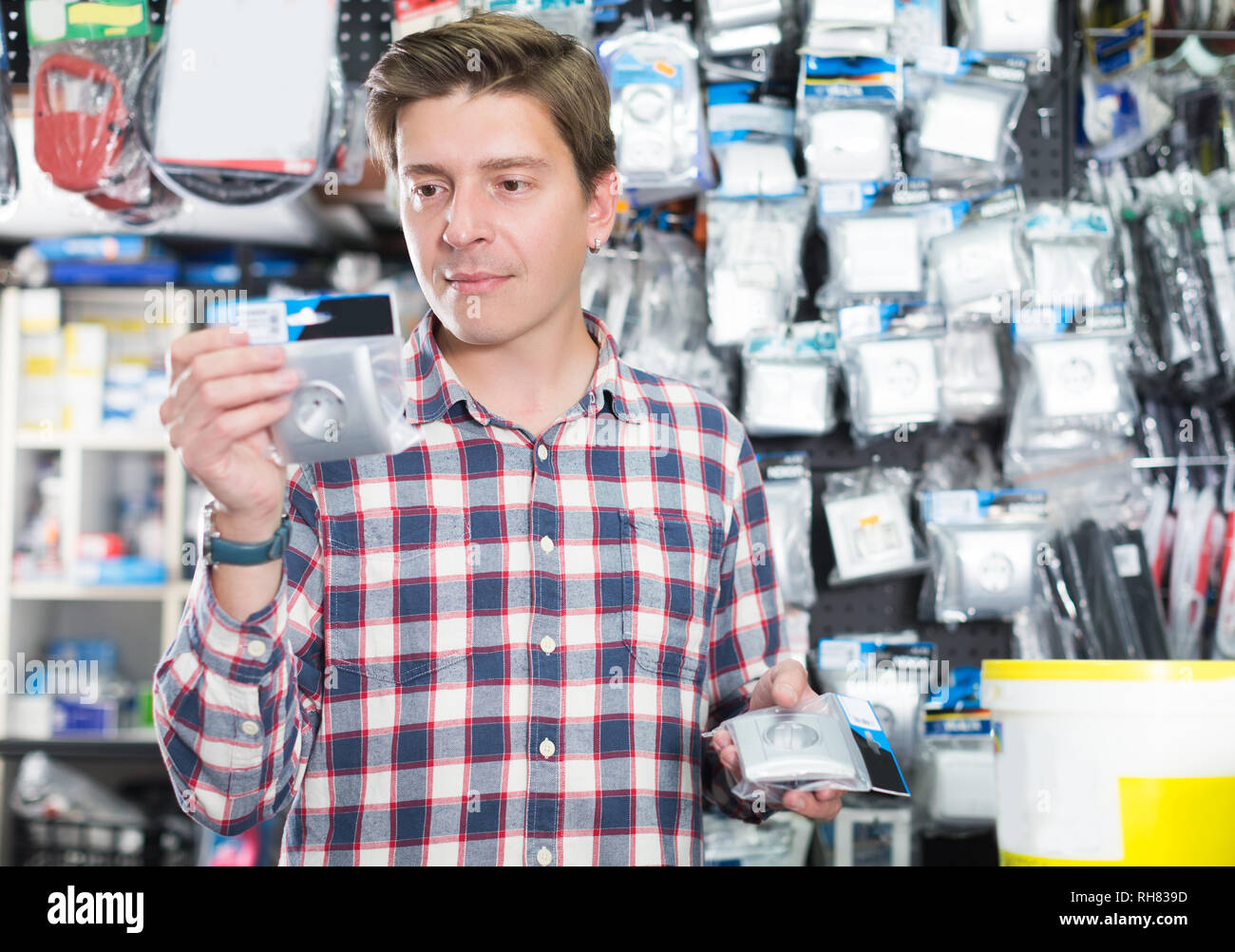 Portrait of positive male choosing electrical installation products ...