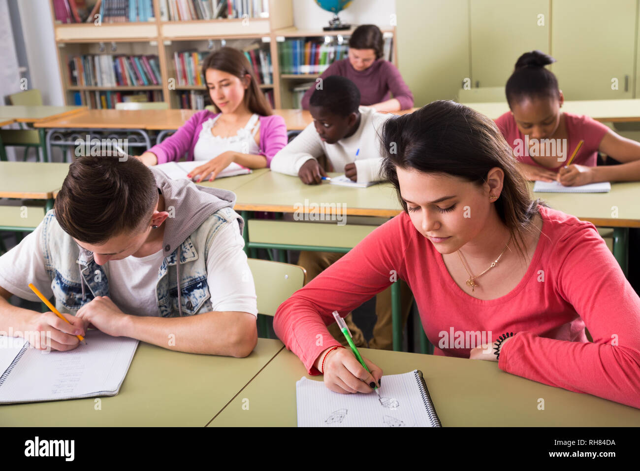 Group of diligent students writing in the notebooks at the lesson in ...