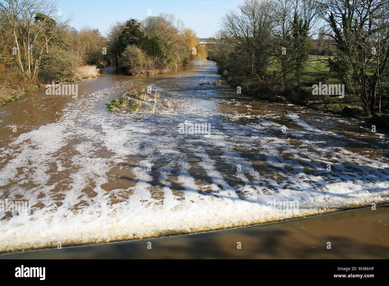 Silt-laden water rushing over a weir on the River Stour Blandford ...