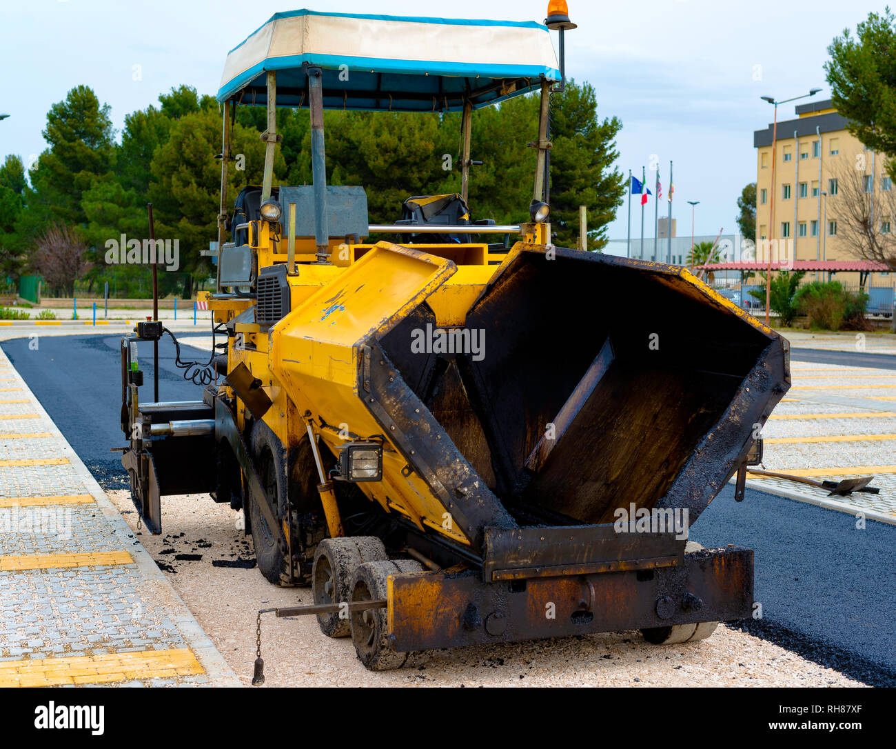 Tracked paver laying fresh asphalt pavement on top of the gravel base ...
