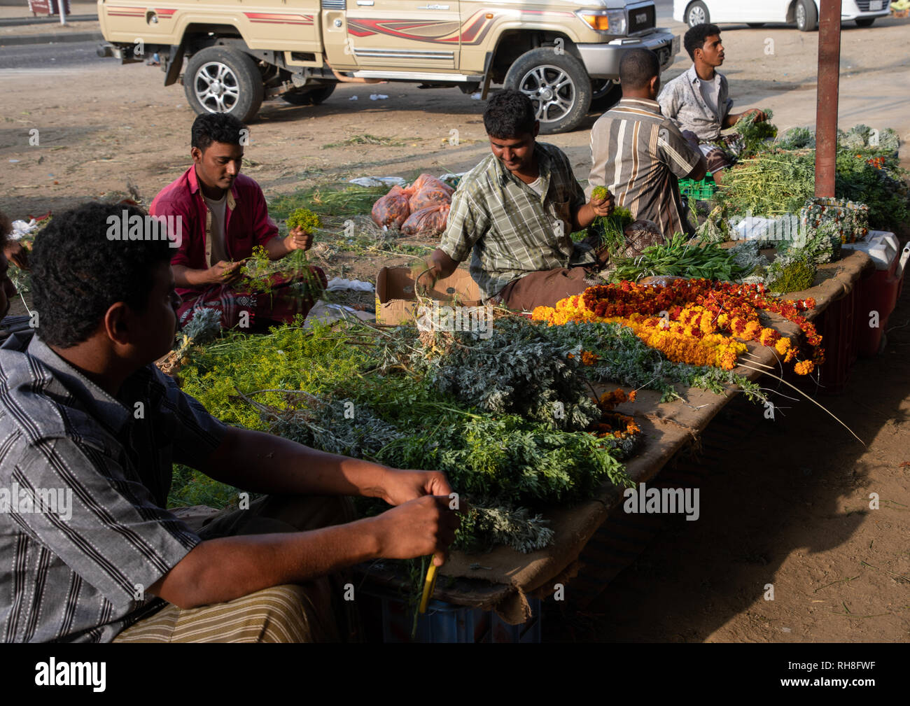 A flower vendor preparing and selling floral garlands and crowns on a ...
