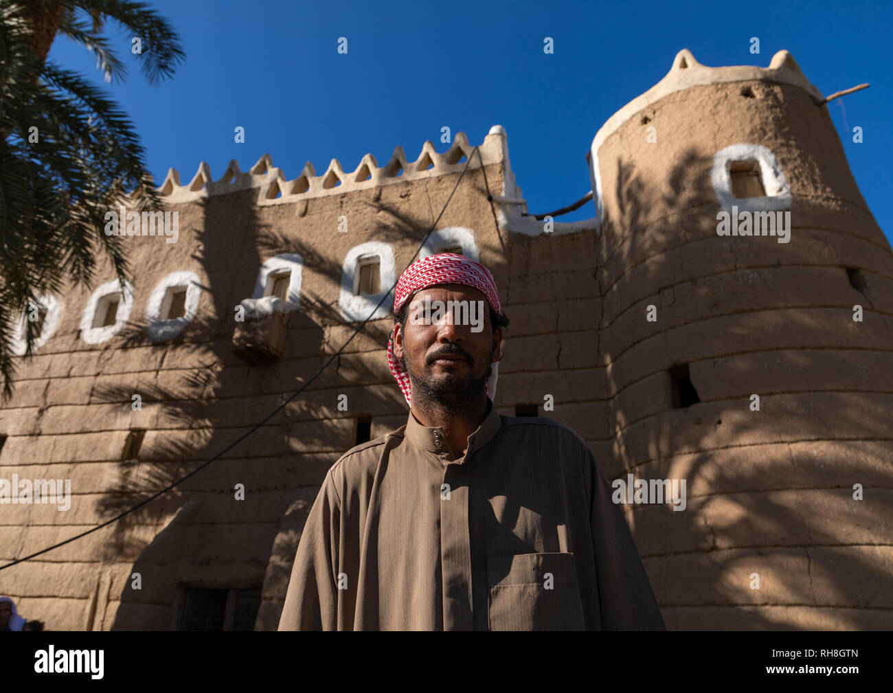 Saudi farmer standing in front of a traditional old mud house, Najran ...