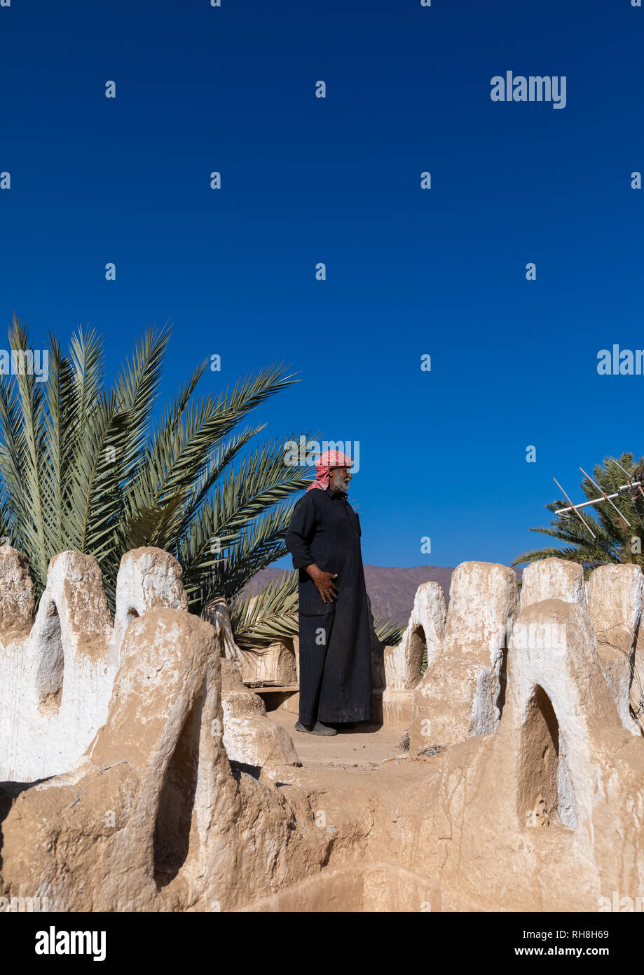 Saudi farmer standing on the terrace of a traditional old mud house ...