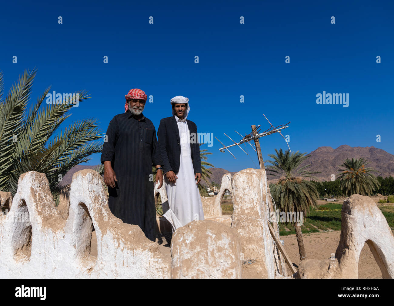 Saudi farmers standing on the terrace of a traditional old mud house ...