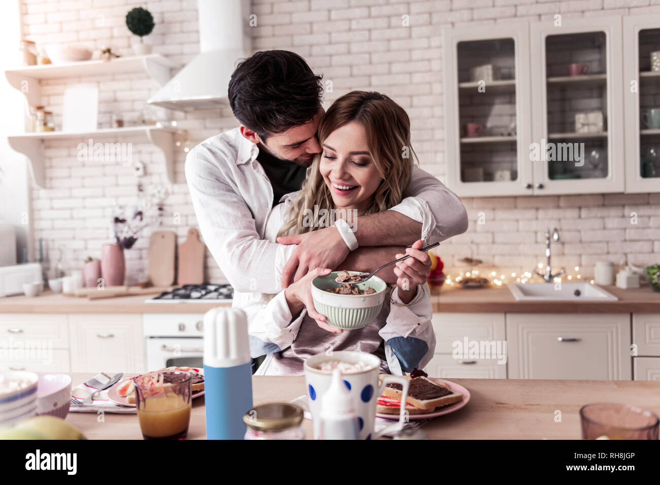 Pretty long-haired young woman in a satin top and her husband spending morning together Stock ...