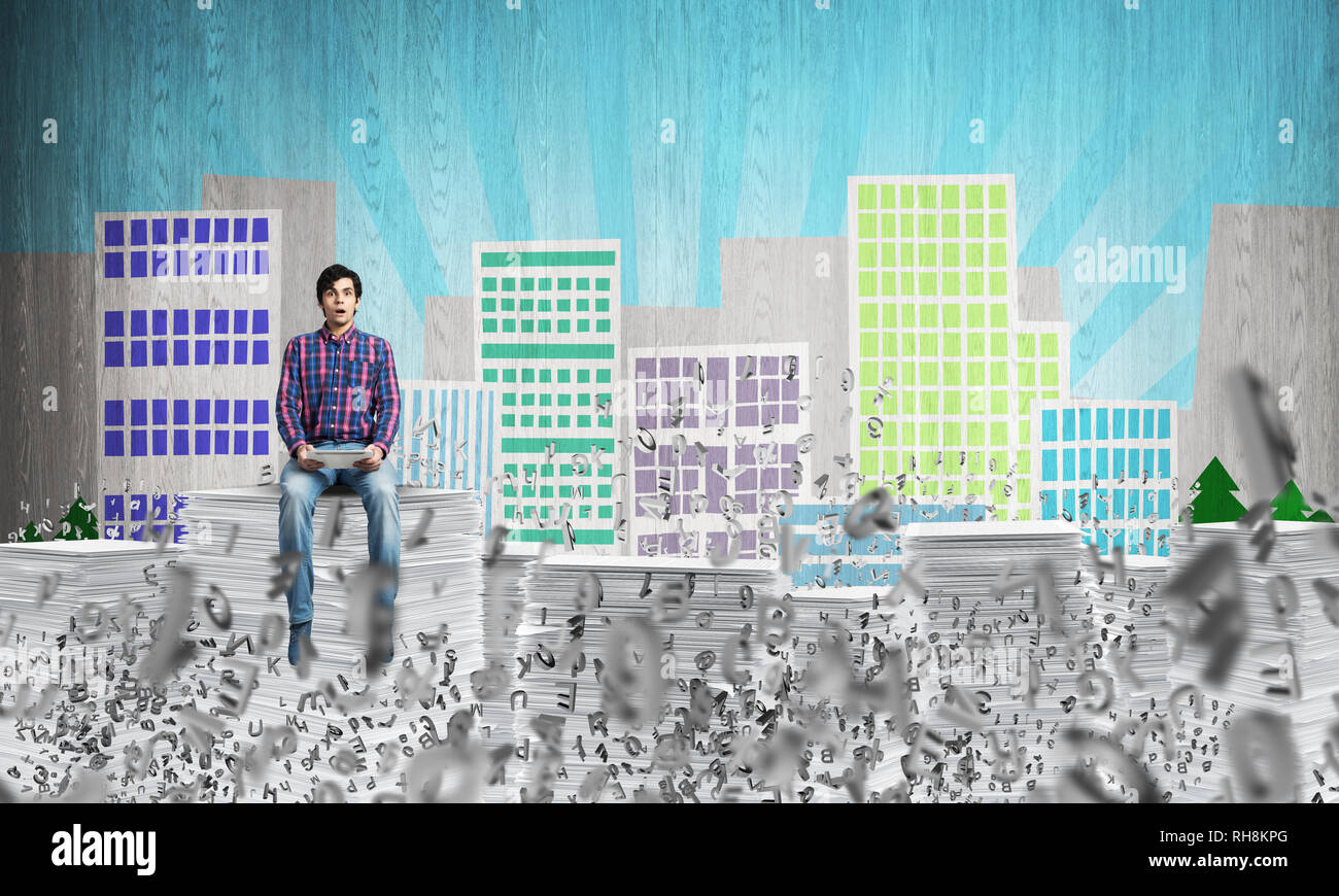 Young man sitting on pile of paper documents Stock Photo - Alamy