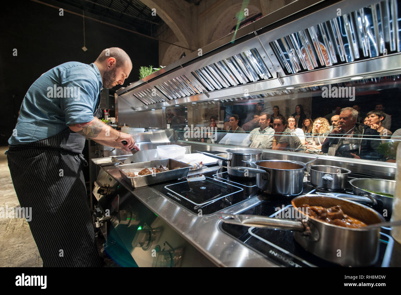 Chef at work during a cooking show. Induction hob in the foreground ...