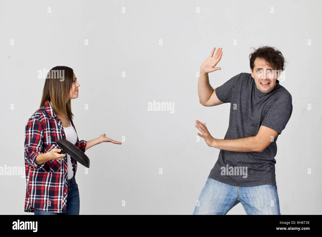 Young couple arguing in kitchen. Frustrated wife with cooking pan ...